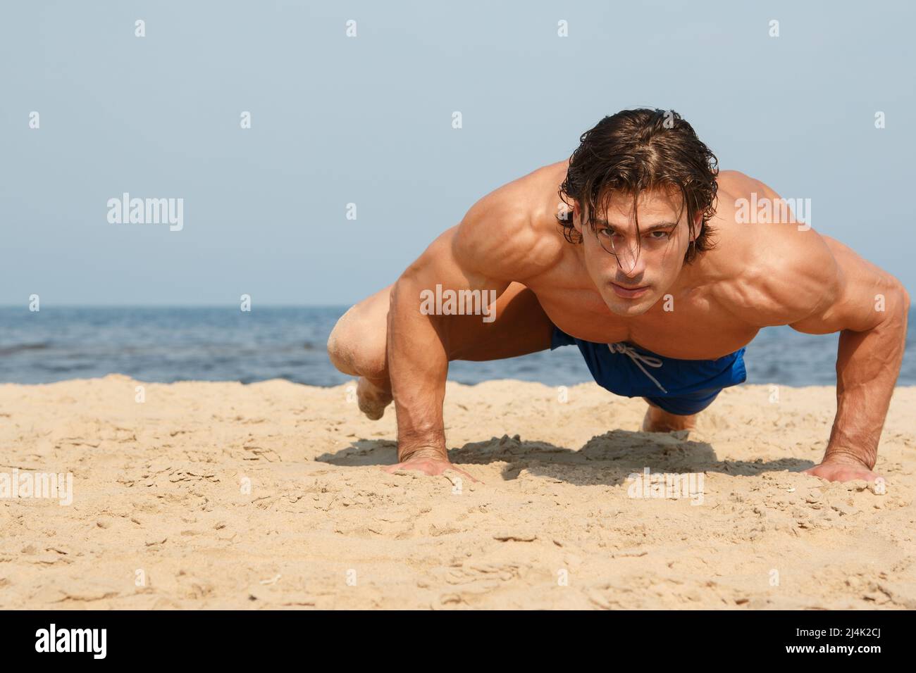 Muscular man during workout on the beach Stock Photo - Alamy
