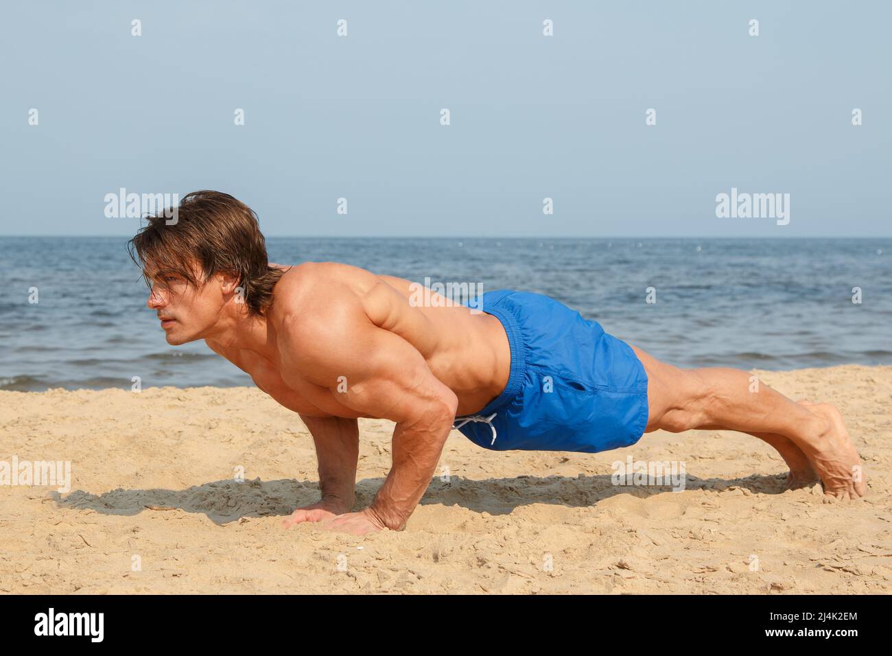 Muscular man during workout on the beach Stock Photo - Alamy