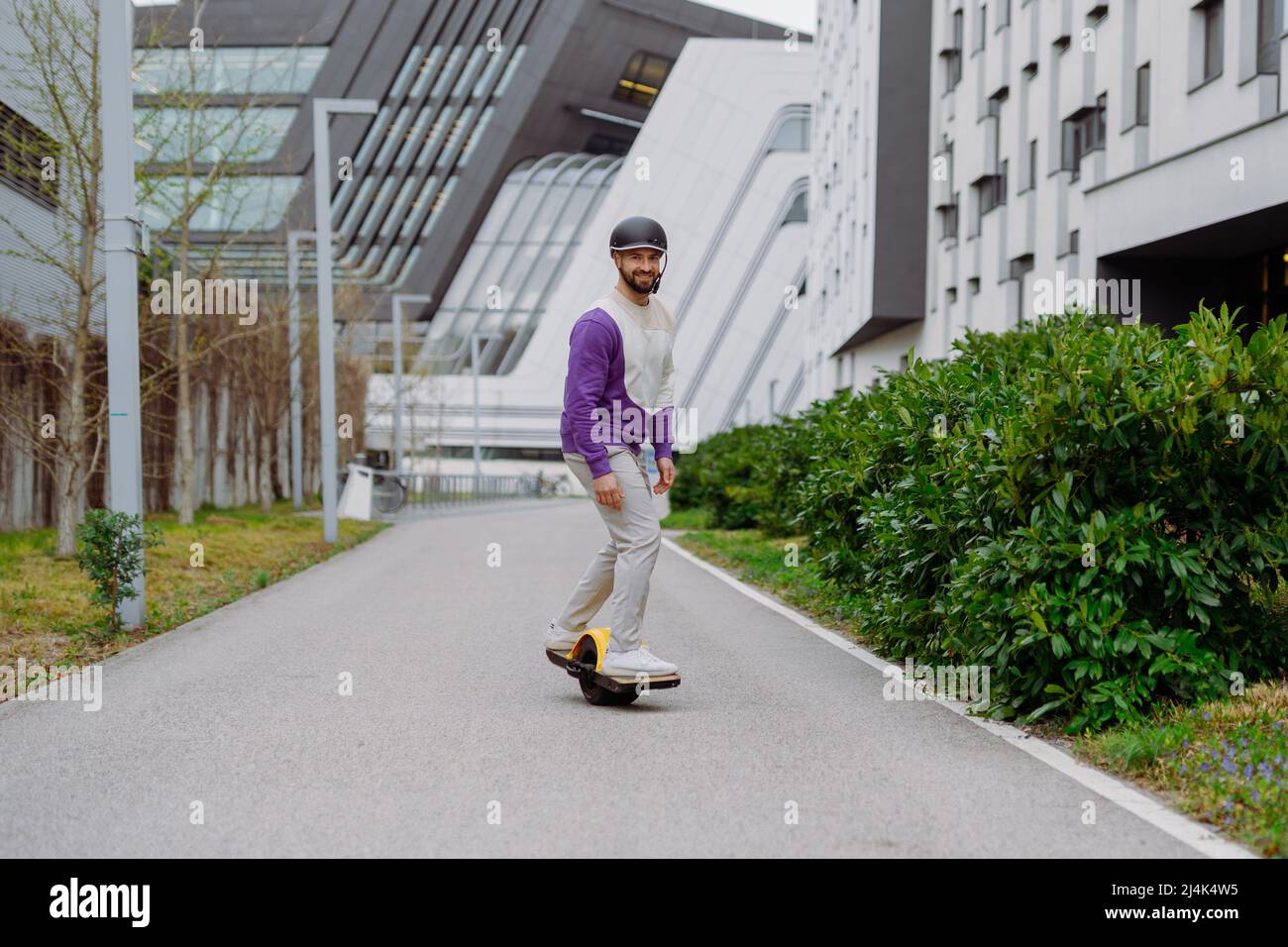 man in a helmet rides an electric skateboard. Onewheel rider in an ...