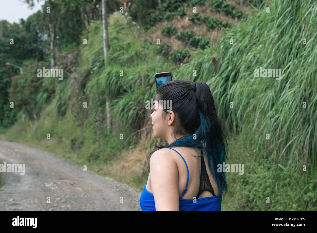 latina girl walking along an ecological trail while documenting nature ...