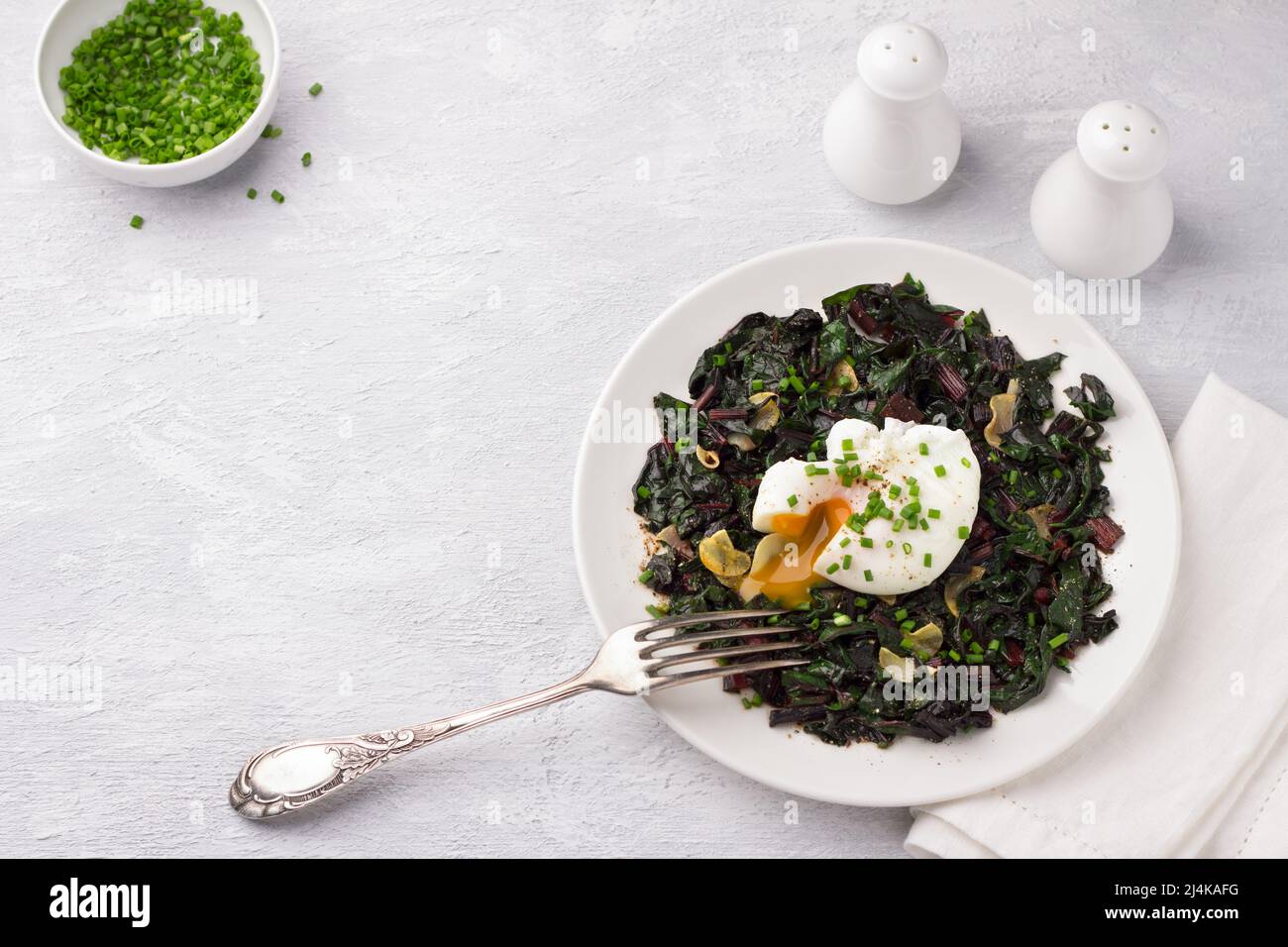Braised chard with garlic and poached egg, seasoned with spices and ...