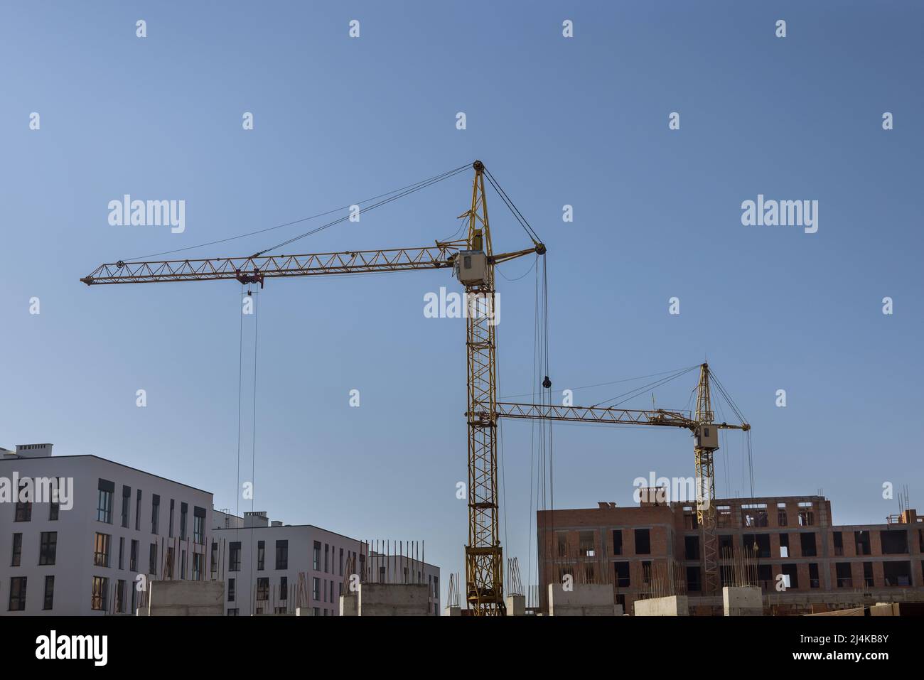 Two tower cranes near building with concrete building under ...
