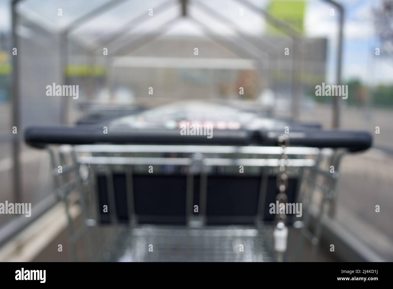 Blurred Row of shopping carts from behind. Black handle and chain ...