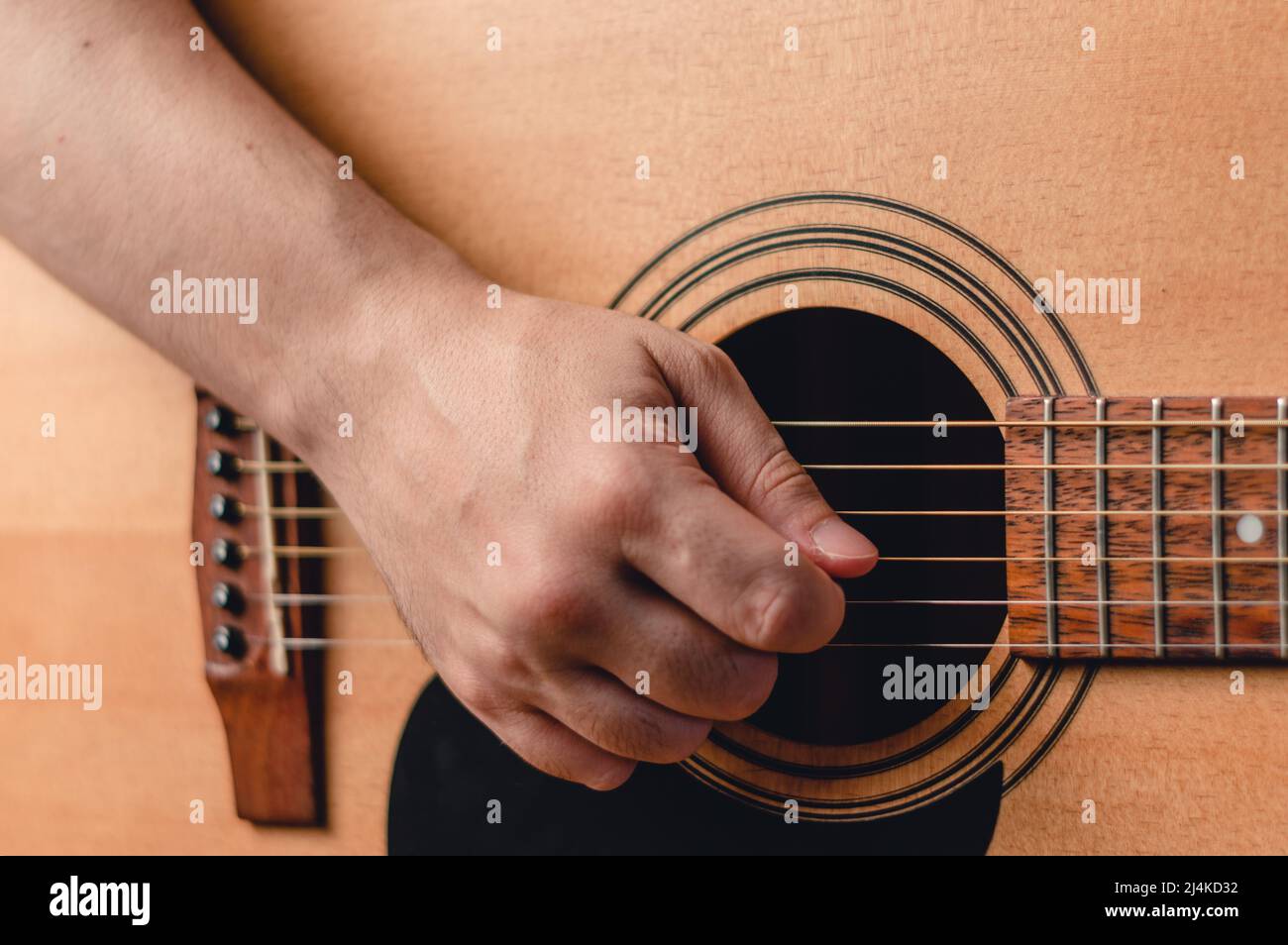closeup front view on soundhole of male caucasian hand playing acoustic ...