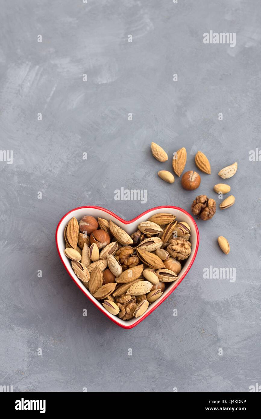 Variety of nuts in red bowl heart shaped on gray background. almonds ...