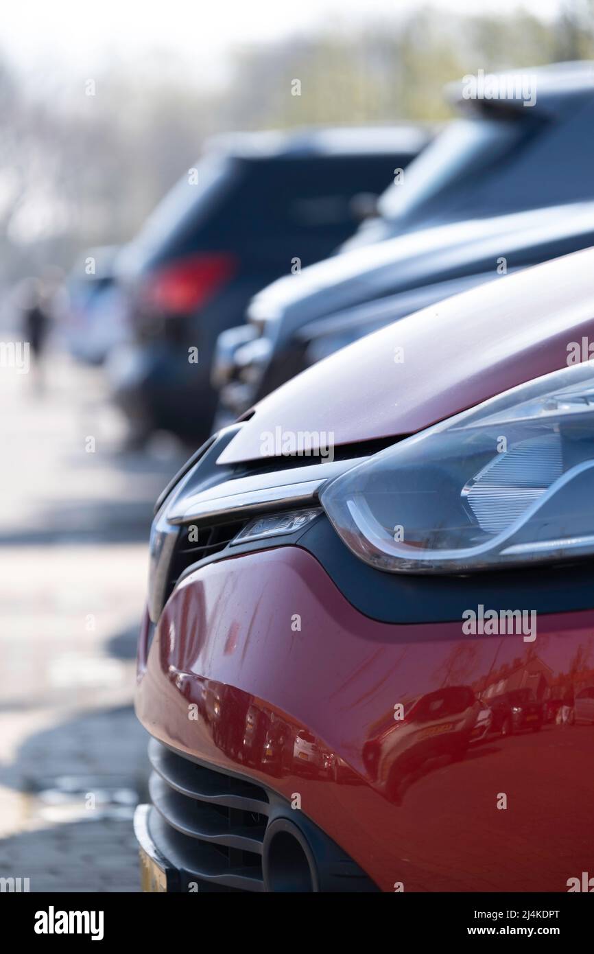 Many cars parked next to each other in a row in a parking lot. Focus on ...