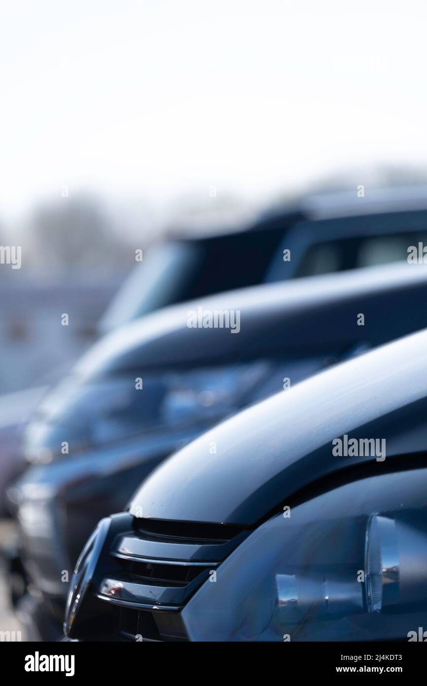 Cars parked next to each other in a row in a parking lot. Focus on the ...