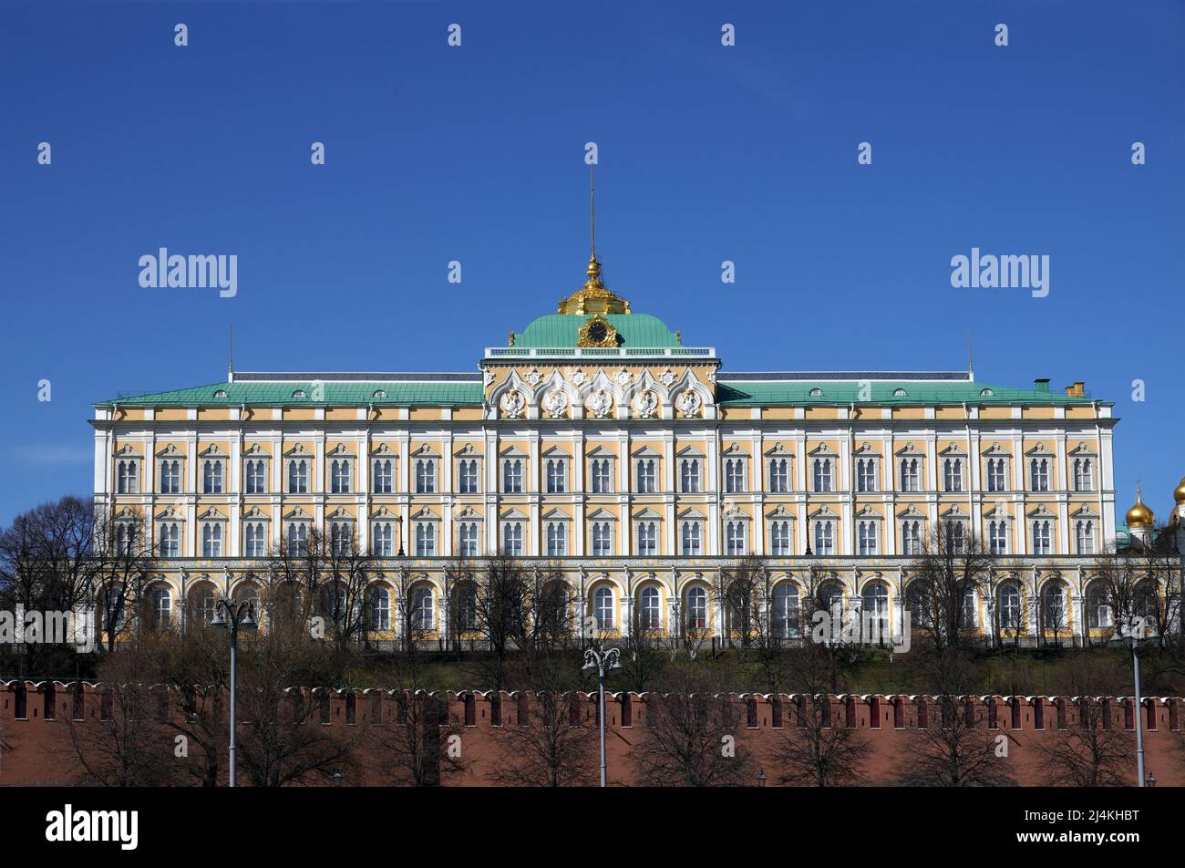 Grand Kremlin Palace with spire on cupola behinf red brick Kremlin wall ...