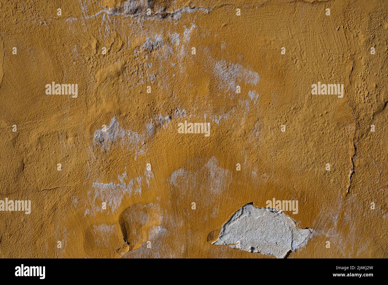 Yellow ochre plaster peeling off weathered wall. Old dirty wall of ...