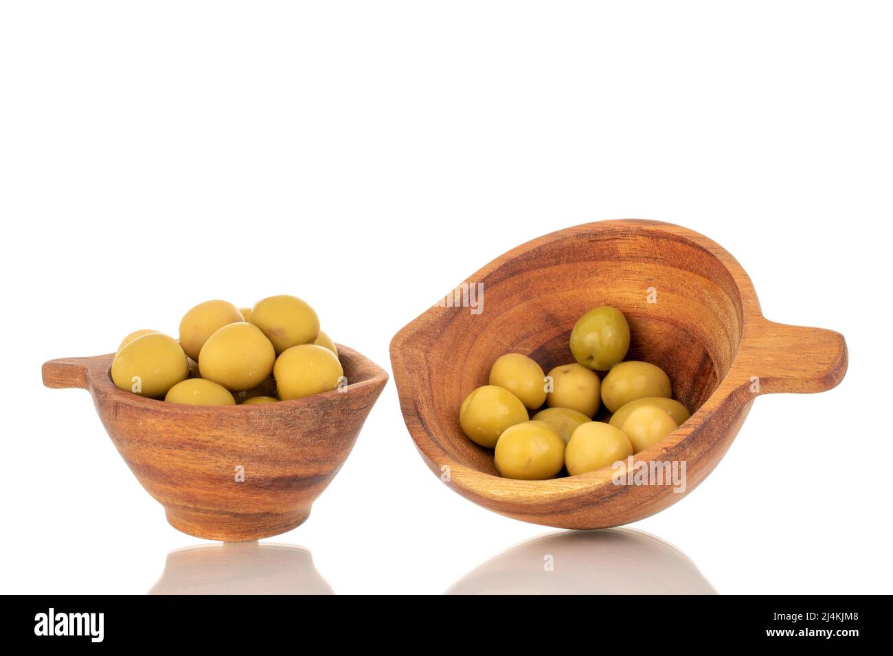 Several green pitted olives in two wooden cups, macro, isolated on ...