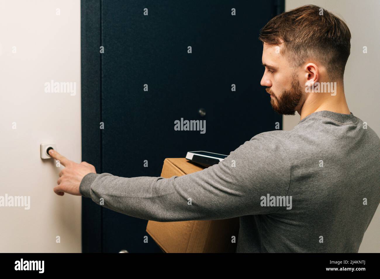 Back view of delivery man holding cardboard box and contactless payment ...