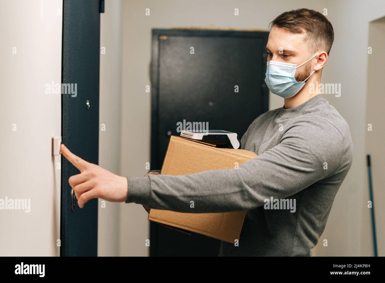 Delivery man wearing medical mask holding cardboard box and contactless ...