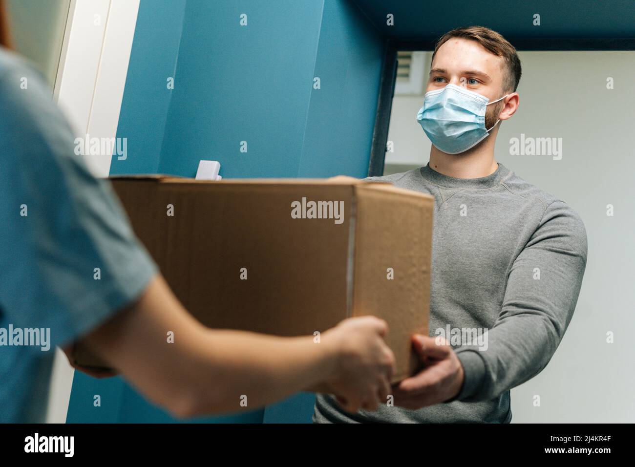 Delivery man wearing medical face mask giving cardboard box parcel to ...