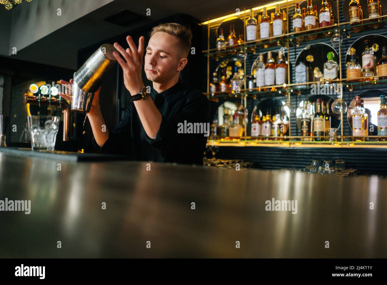 Low-angle view of bartender male mixing ingredients of fresh cocktail ...