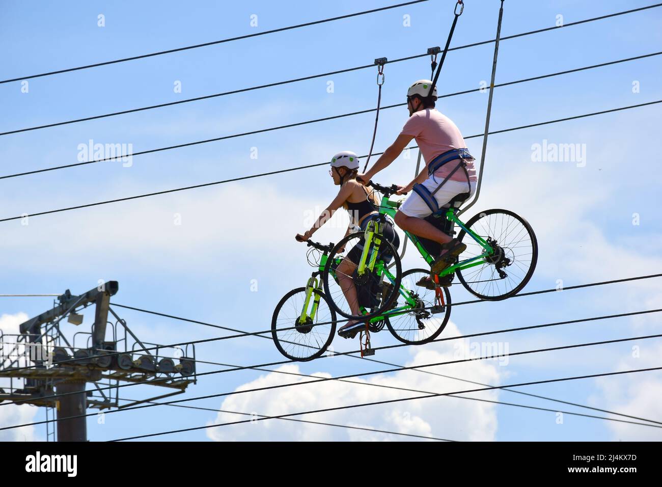 At the attraction, a guy and a girl ride on bicycles on hanging ropes ...
