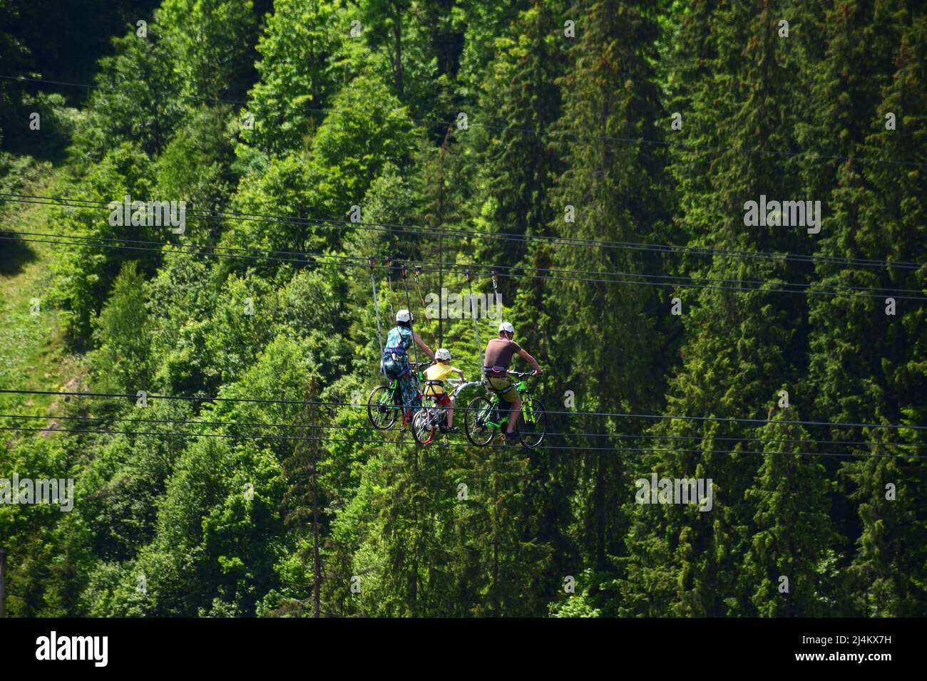 A family of three ride the attraction on bicycles on ropes above the ...