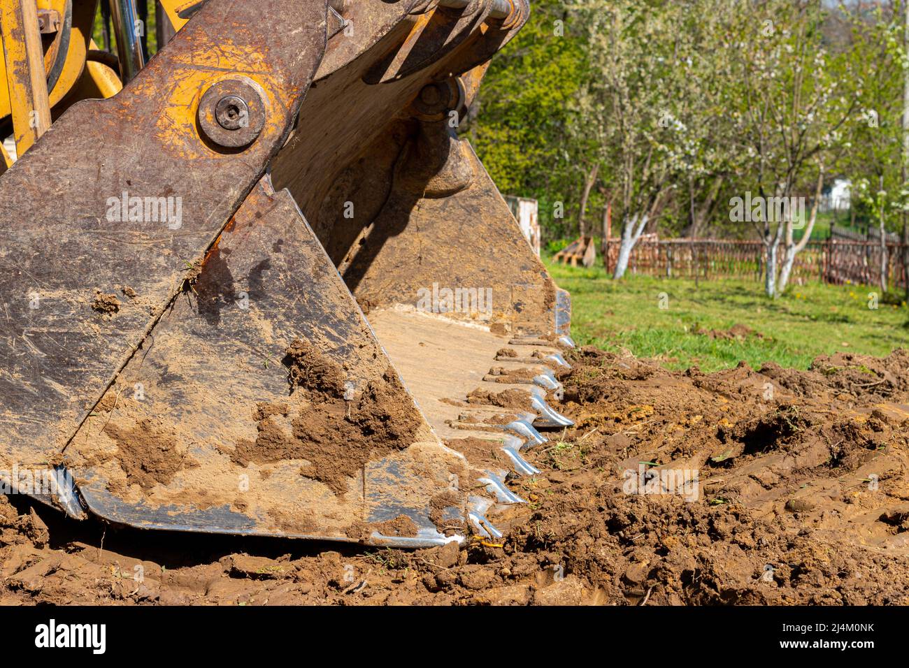 Clearing and leveling a private land plot. Yellow excavator driving ...