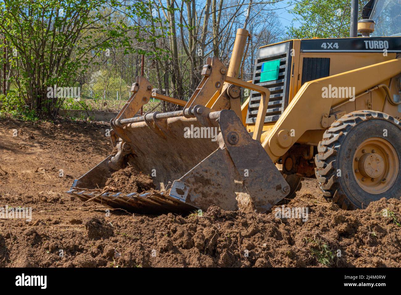 Clearing and leveling a private land plot. Yellow excavator driving ...