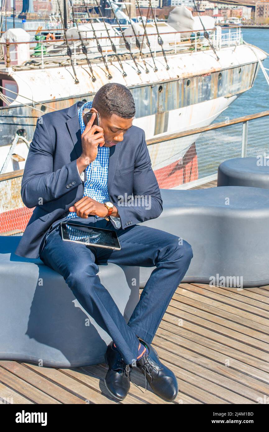 Dressing in a blue suit, leather shoes, a tablet computer on his lap, a ...