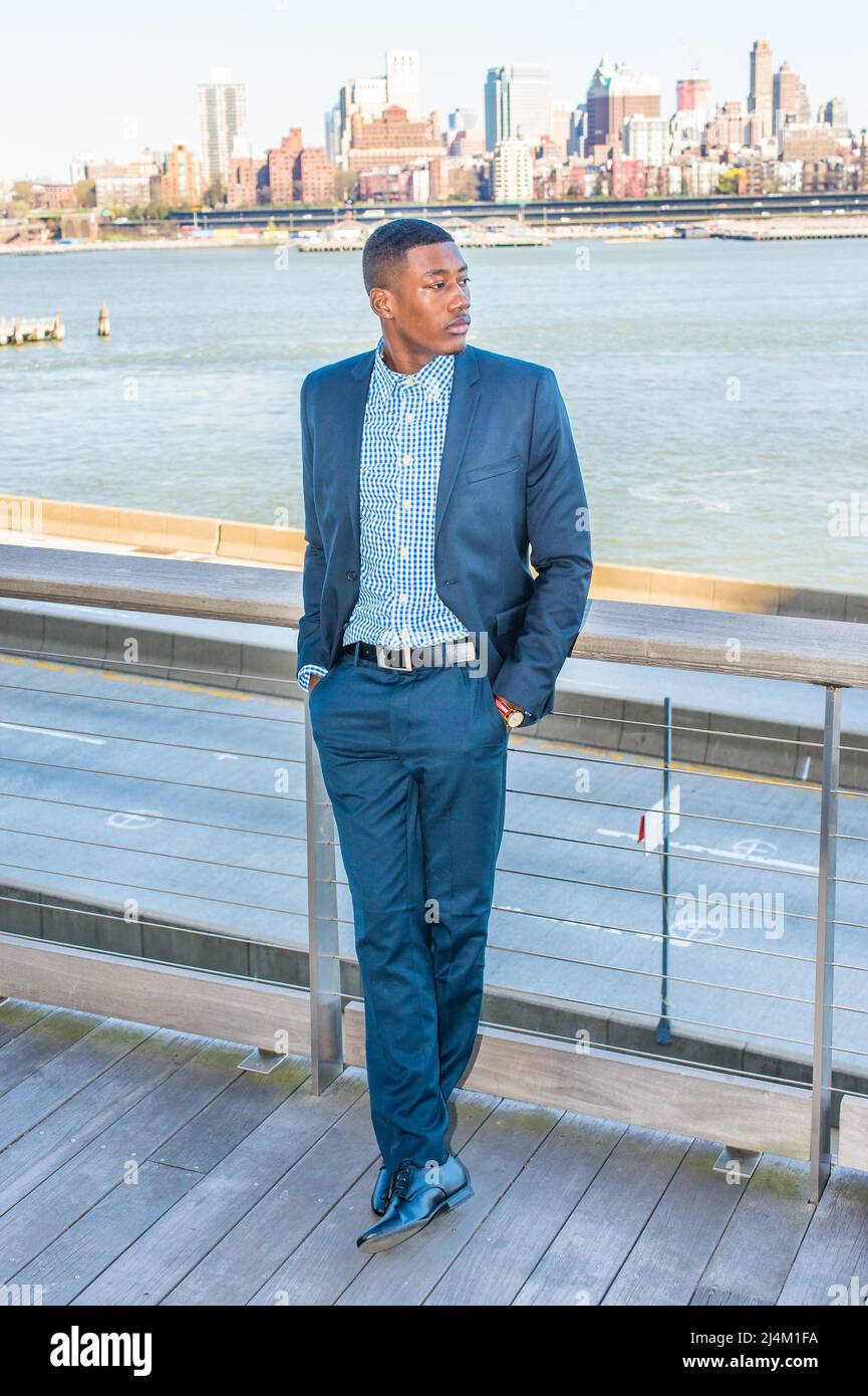 Two hands putting in pockets, crossing legs, a young black businessman ...