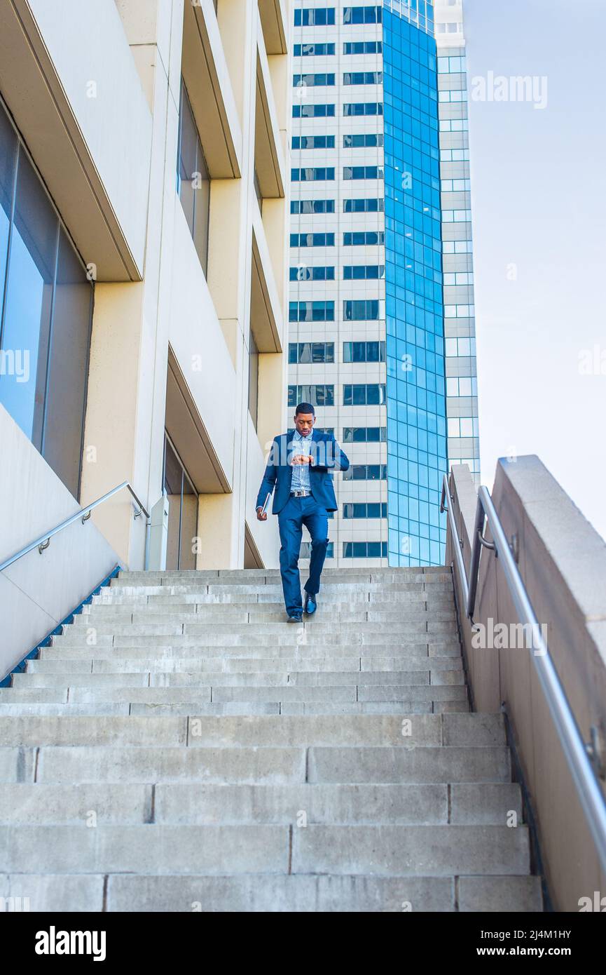 Holding a tablet computer, looking at his wristwatch, a young handsome ...