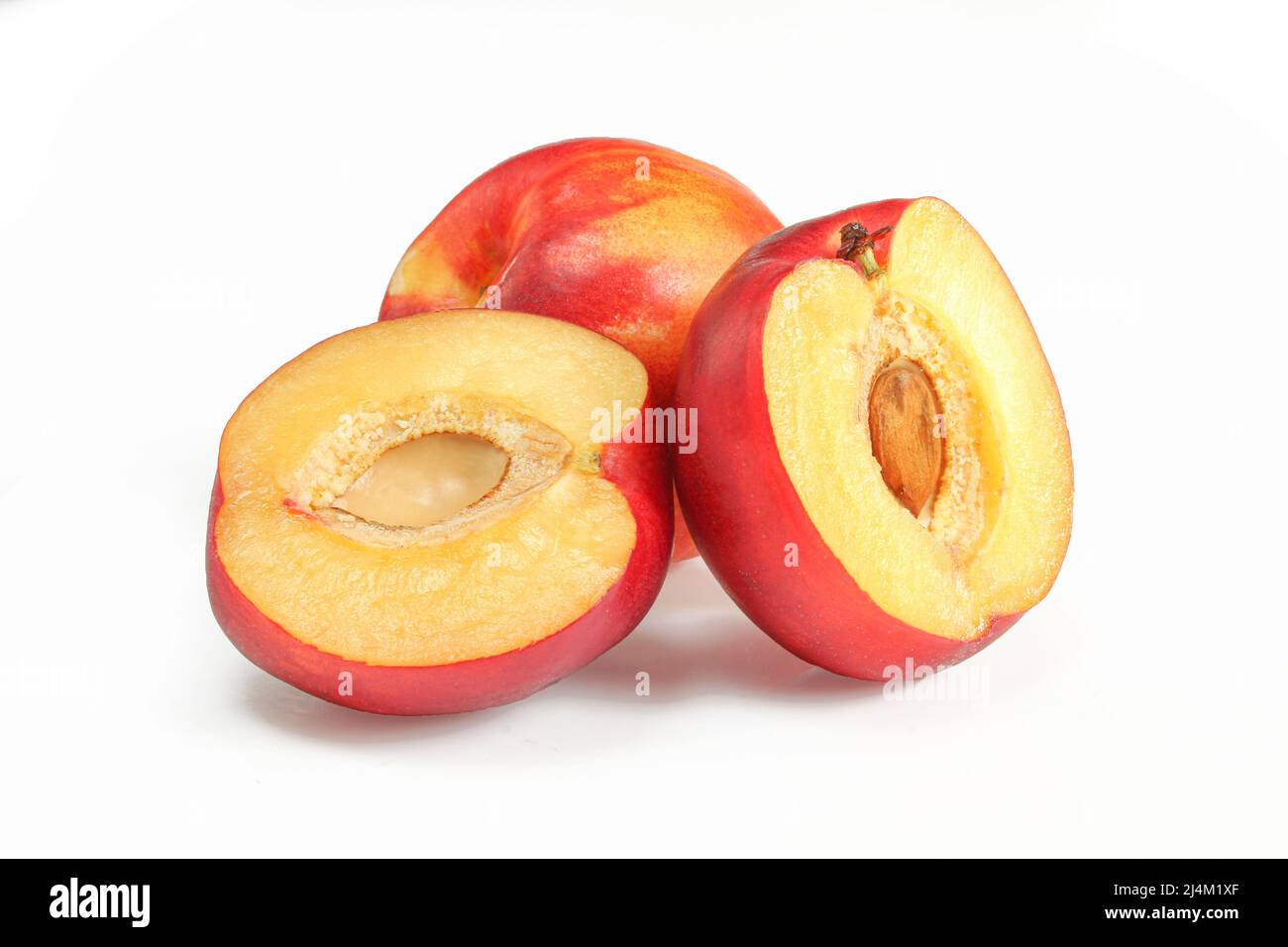 Whole and sliced nectarine with visible seed core isolated on white ...
