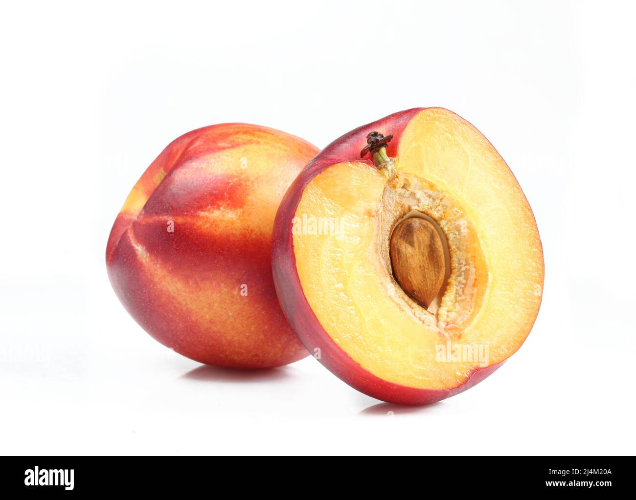 Whole and sliced nectarine with visible seed core isolated on white ...