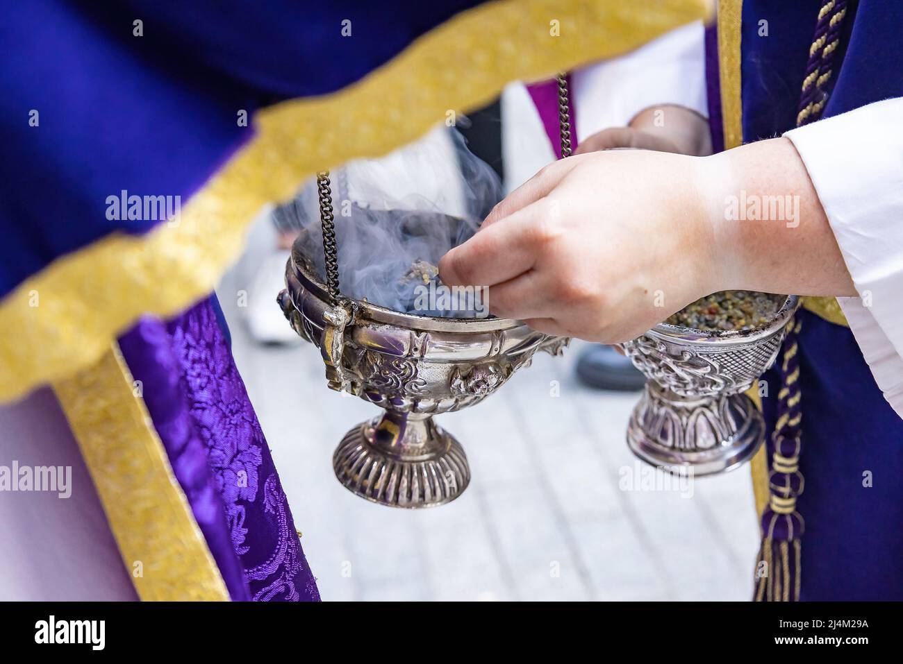 An altar boy or acolyte in a Holy Week procession filling one of the ...