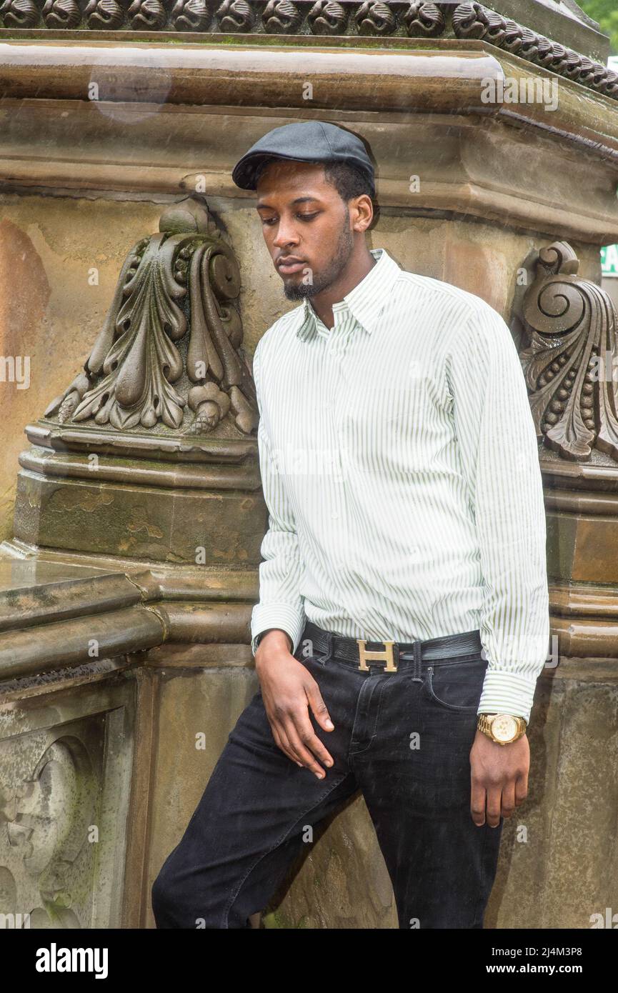 In the raining, a young handsome black guy is standing outside and into ...