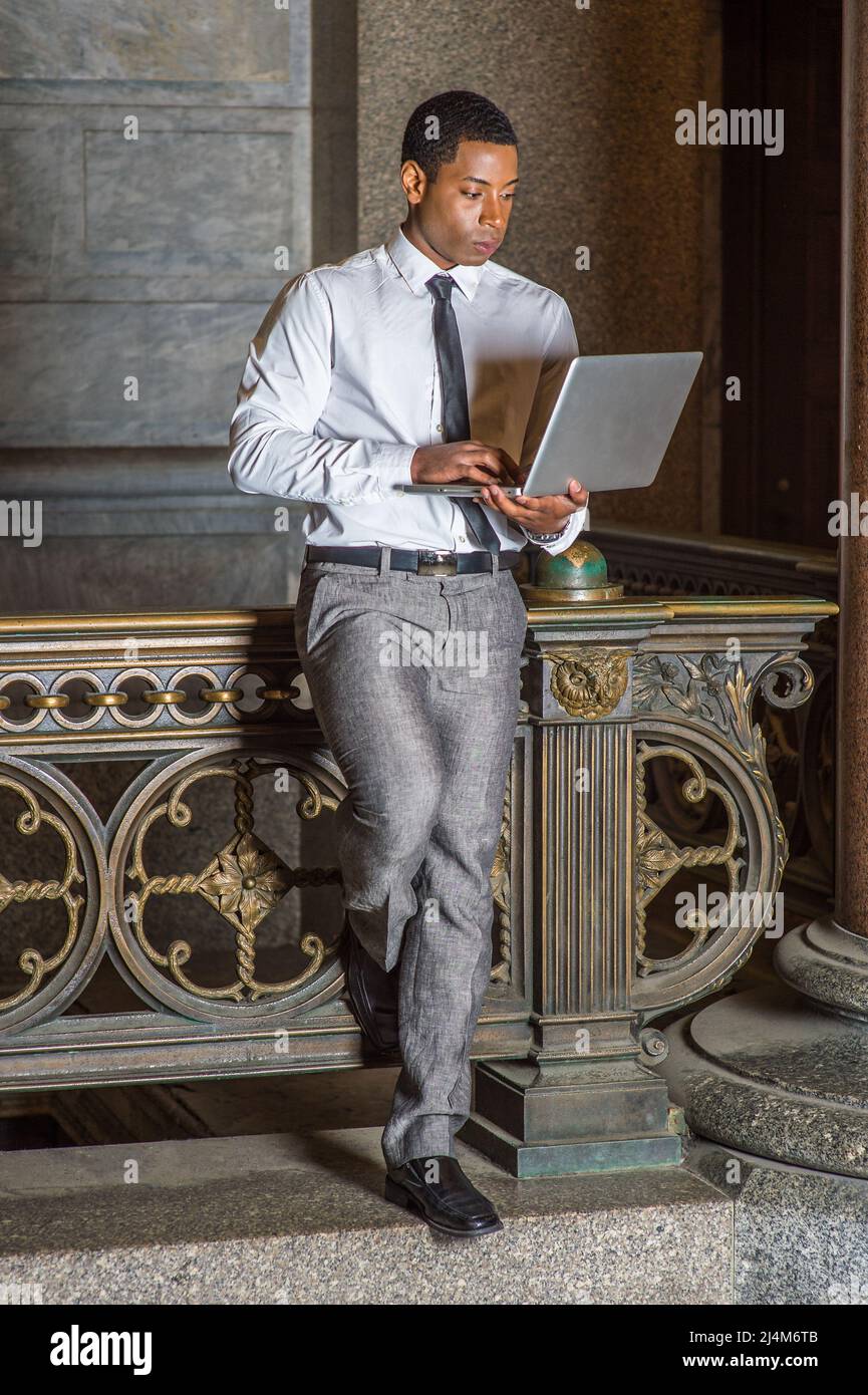 Wearing a white shirt, a black tie, gray pants, a young handsome black ...