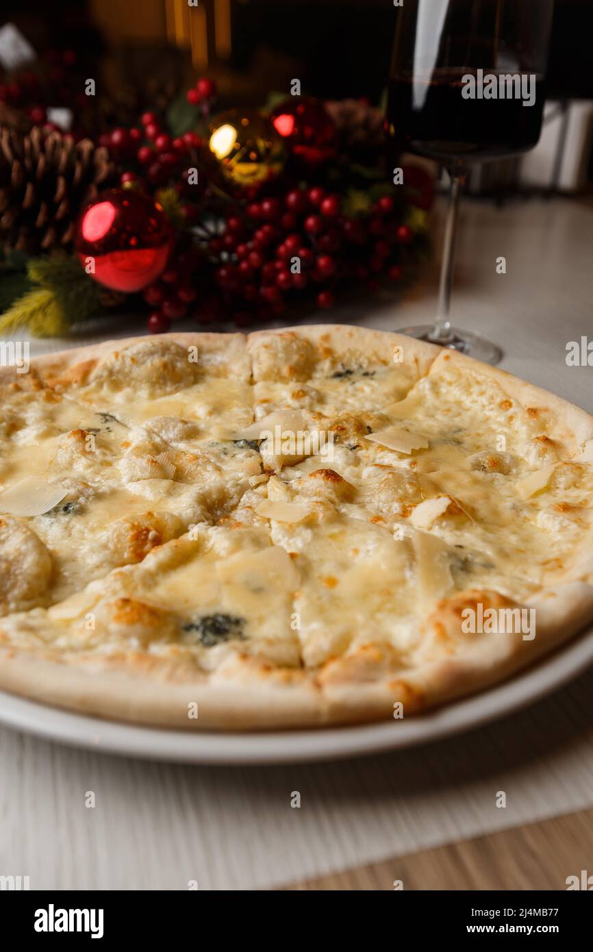 Four cheese pizza quattro formaggi with glass of wine on background with new year decorations ...