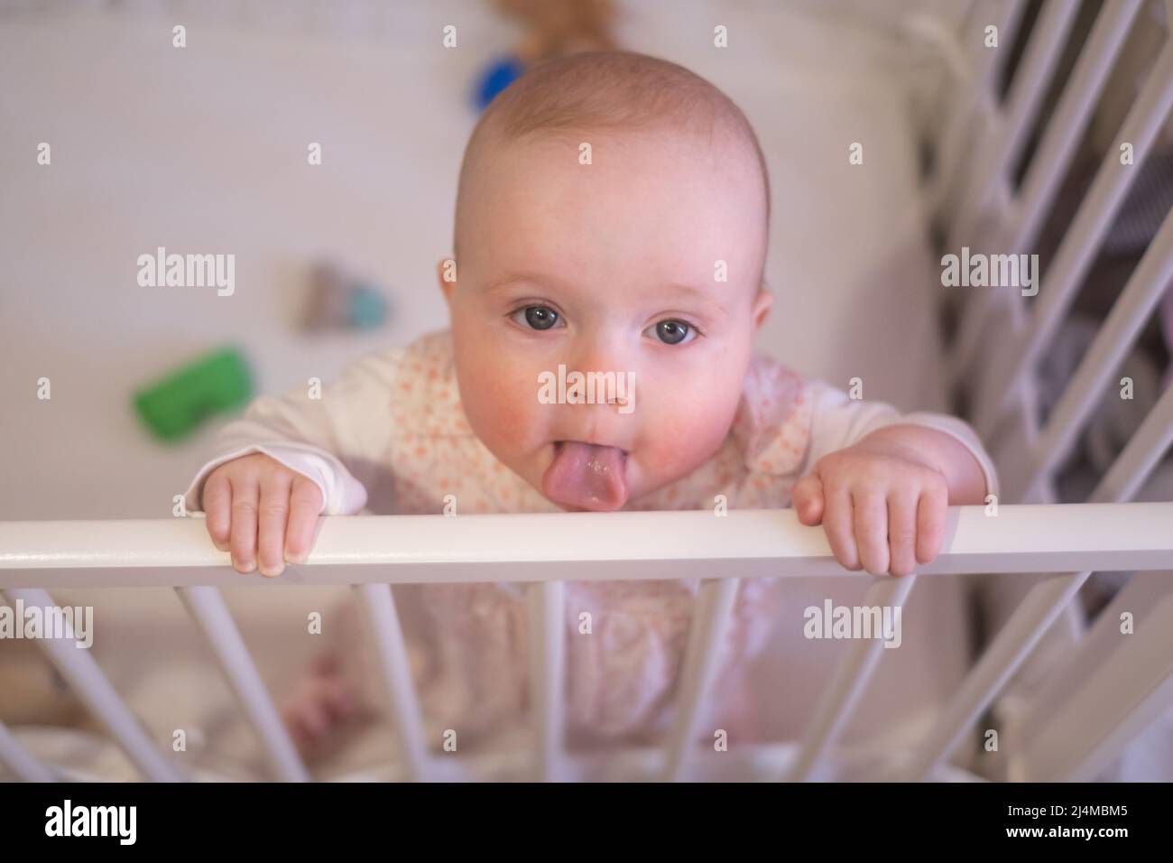 Cute little baby standing in crib at home. Waking up on the morning ...
