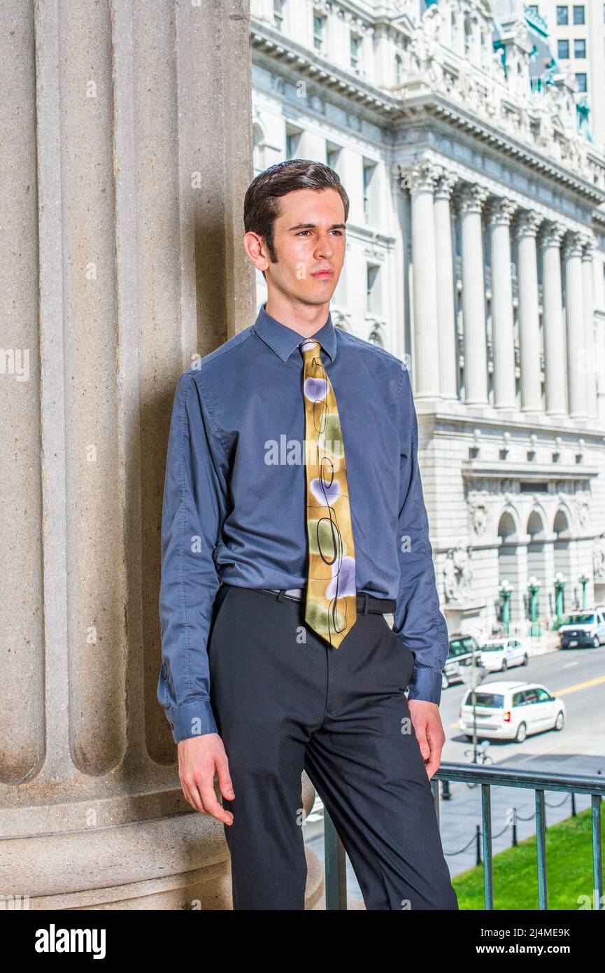 Dressing in a blue shirt, black pants, a colorful tie, a young college ...