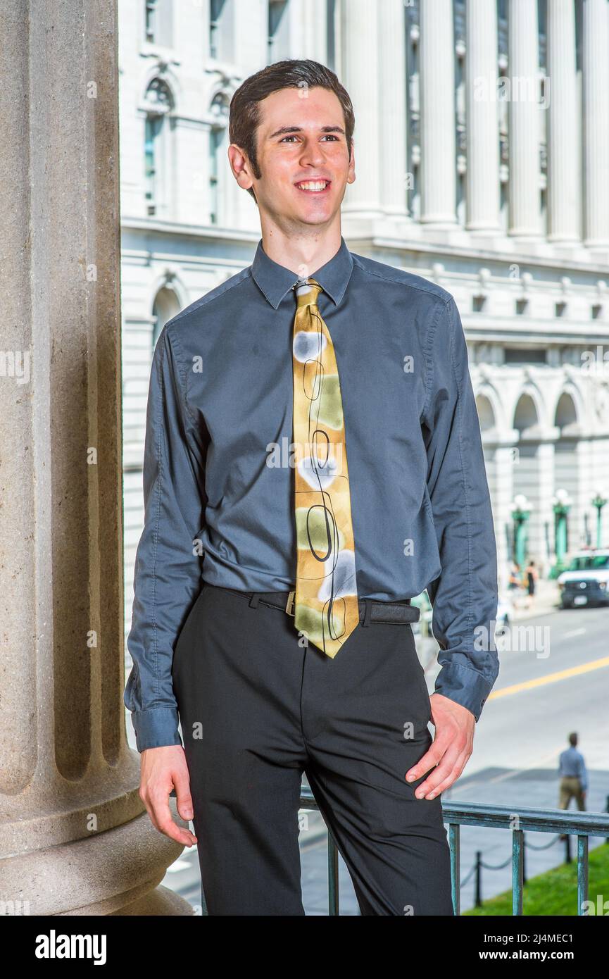 Dressing in a blue shirt, black pants, a colorful tie, a young college ...