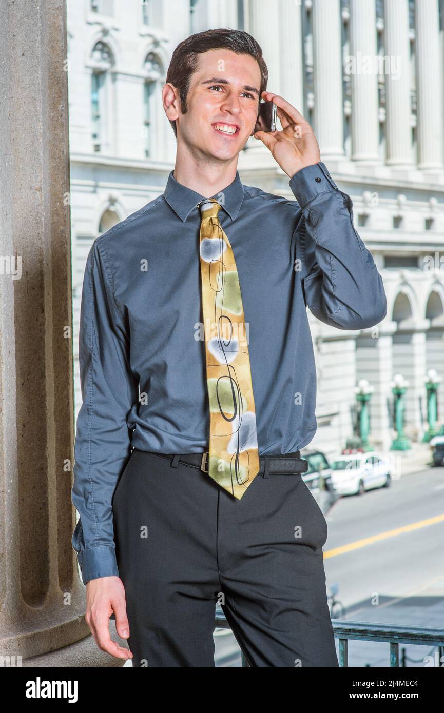 Dressing in a blue shirt, black pants, a colorful tie, a young college ...