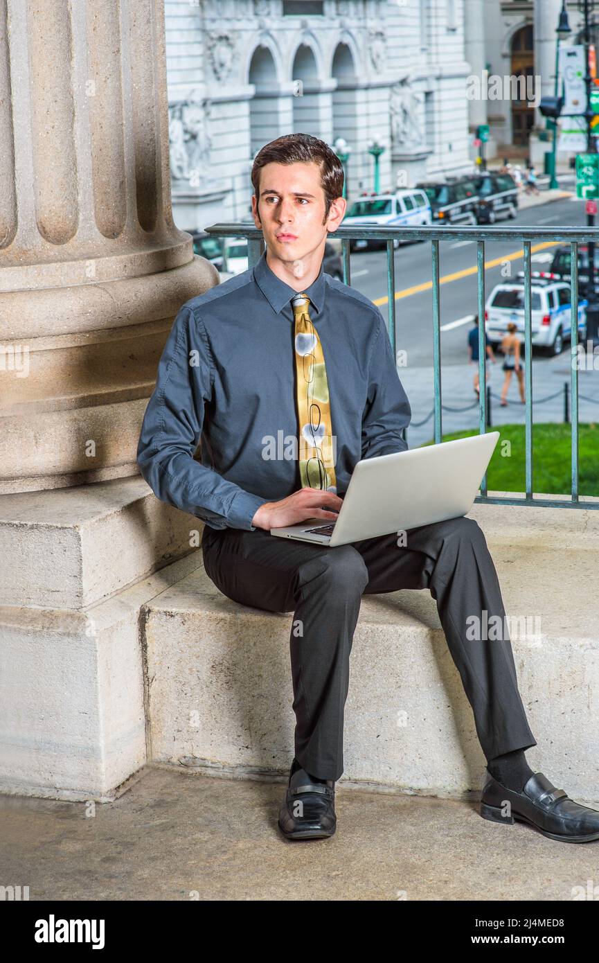 Dressing in a blue shirt, black pants, a colorful tie, a young college ...