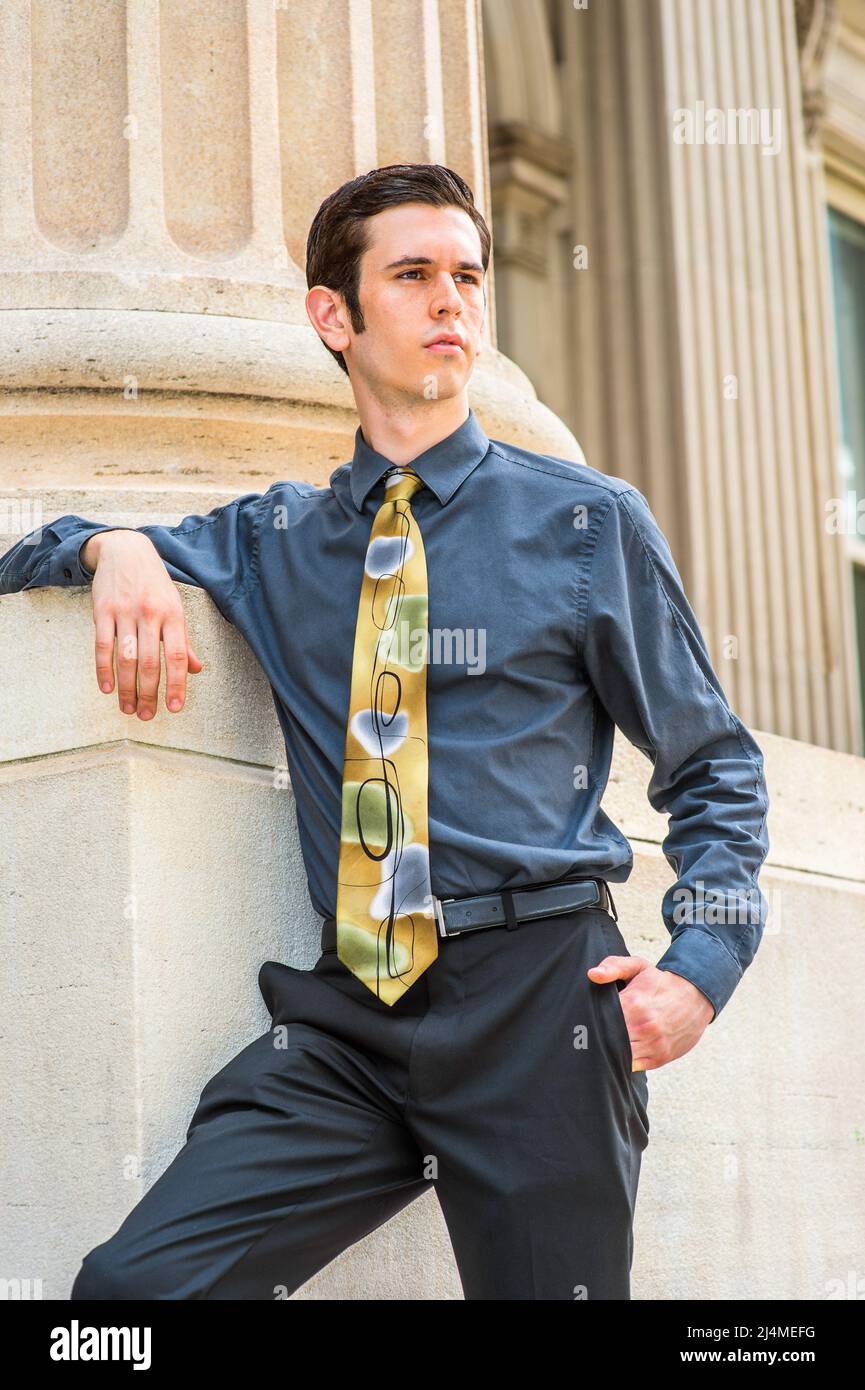Dressing in a blue shirt, black pants, a colorful tie, a young college ...