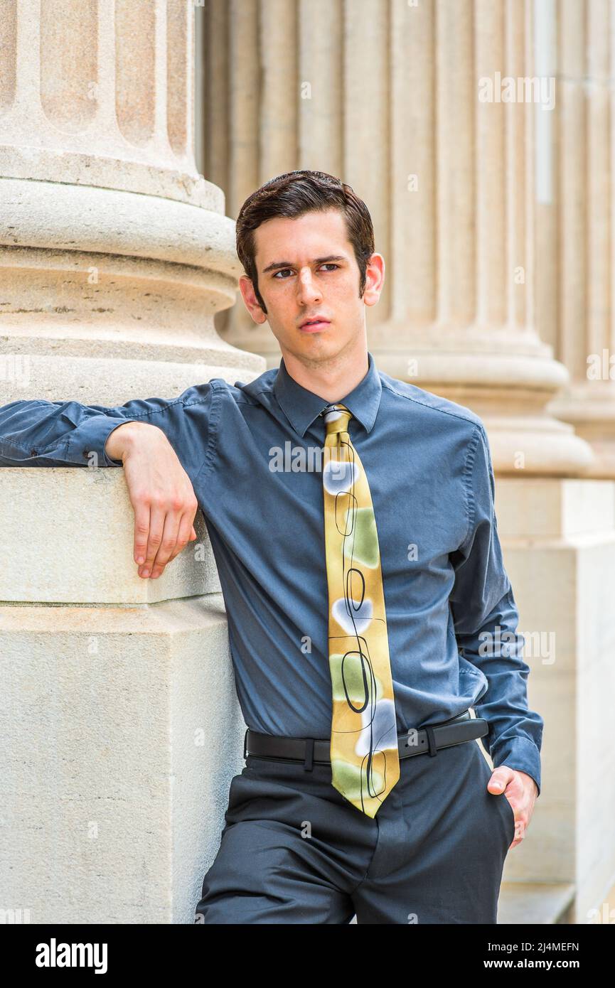 Dressing in a blue shirt, black pants, a colorful tie, a young college ...