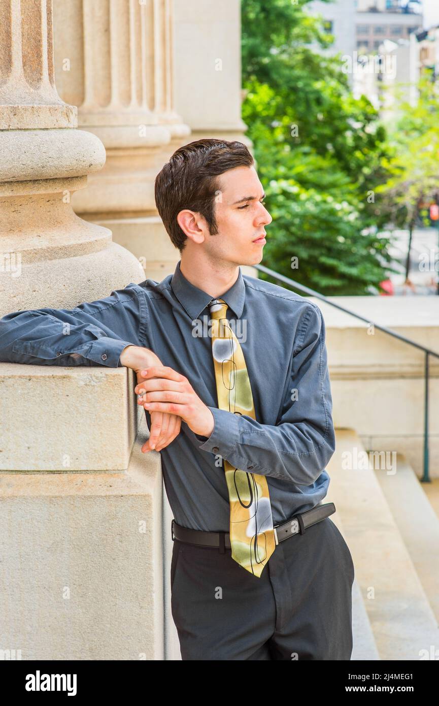 Dressing in a blue shirt, black pants, a colorful tie, a young college ...