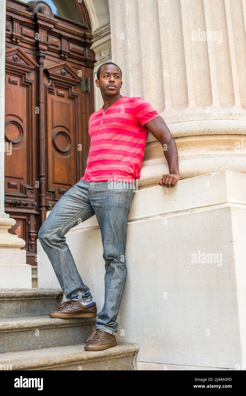 A young black graduate student is standing outside an office building ...