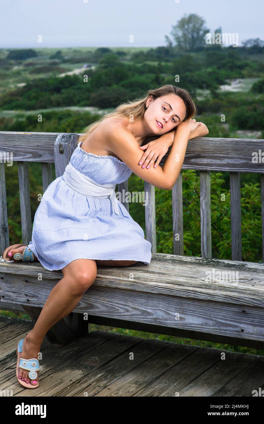 Dressing In A White Blue Dress A White Waistband And Sandals A Pretty Blonde Girl Is Sitting