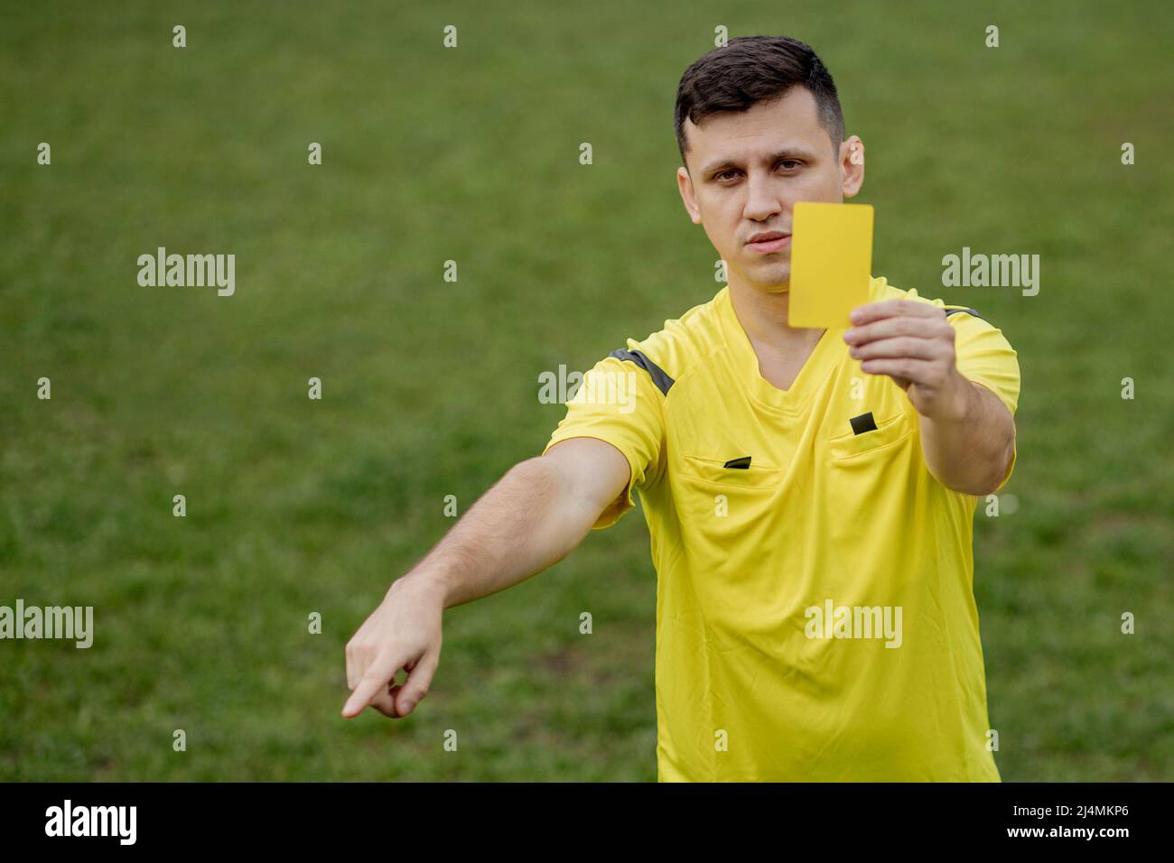 Angry football referee showing a yellow card and pointing with his hand ...