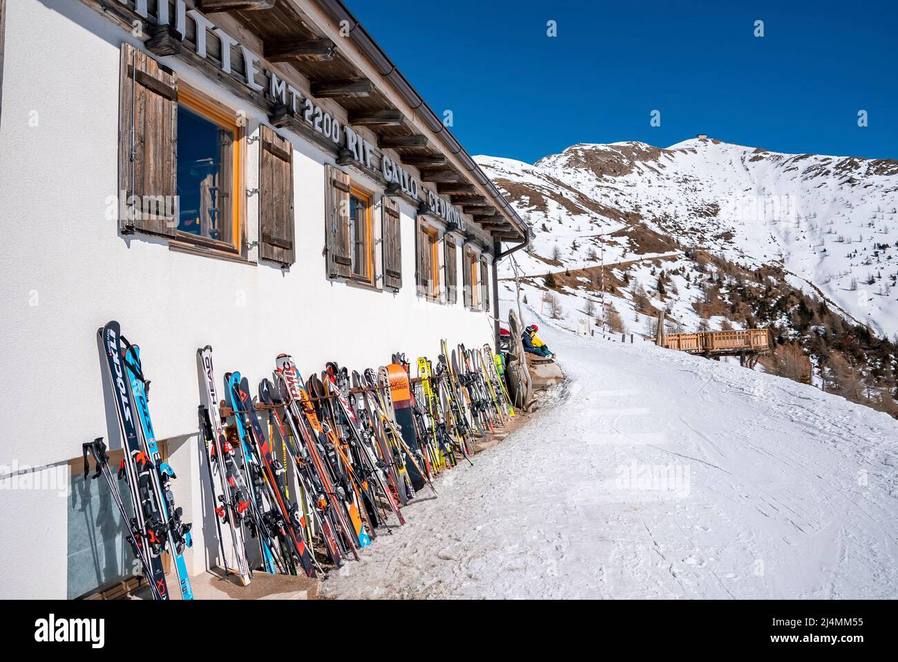 Pairs of colorful skis on stone wall at ski resort on mountain slope ...