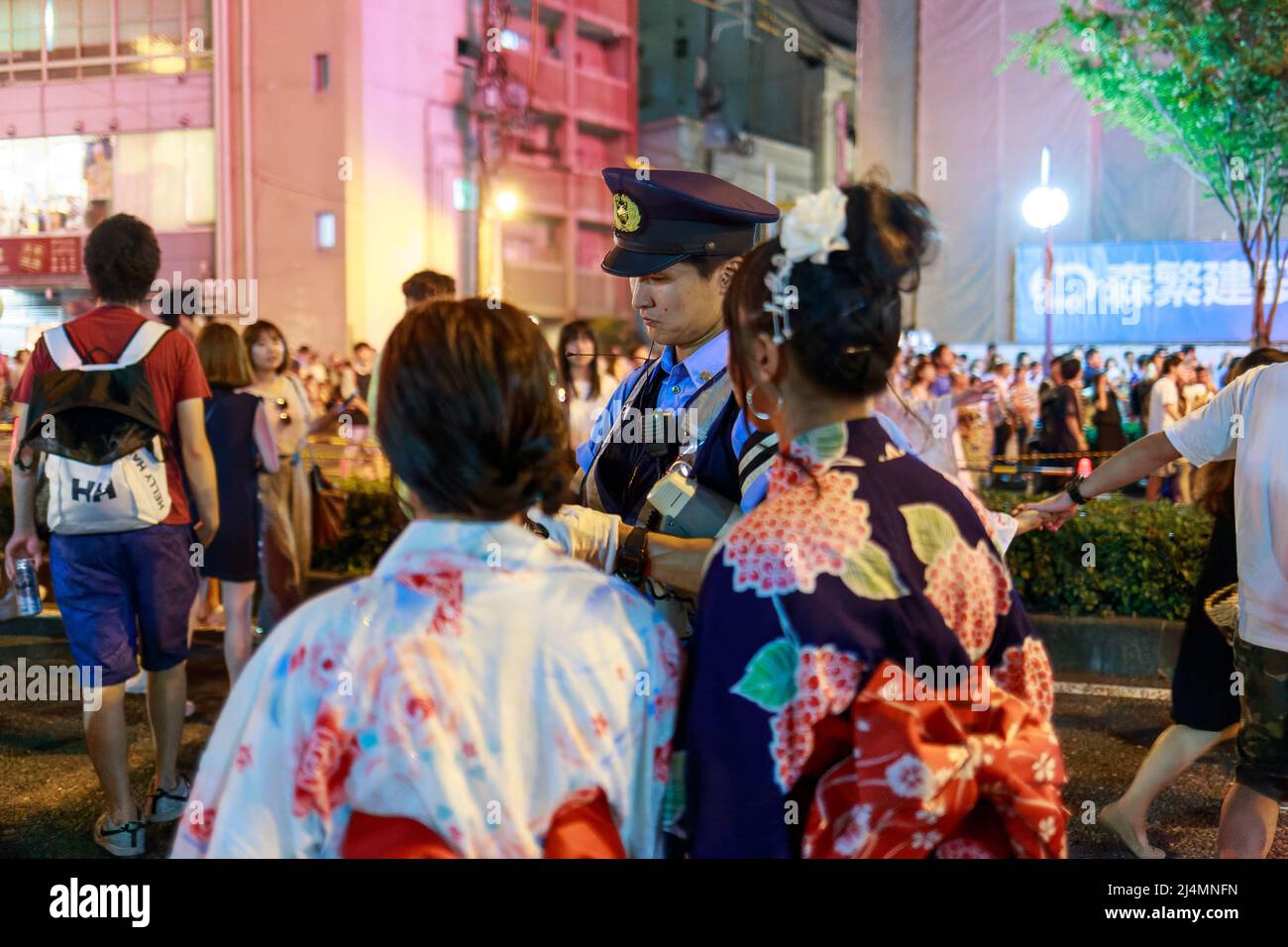 Osaka, Japan - July 25, 2015: Police officer gives directions to women wearing kimonos on ...