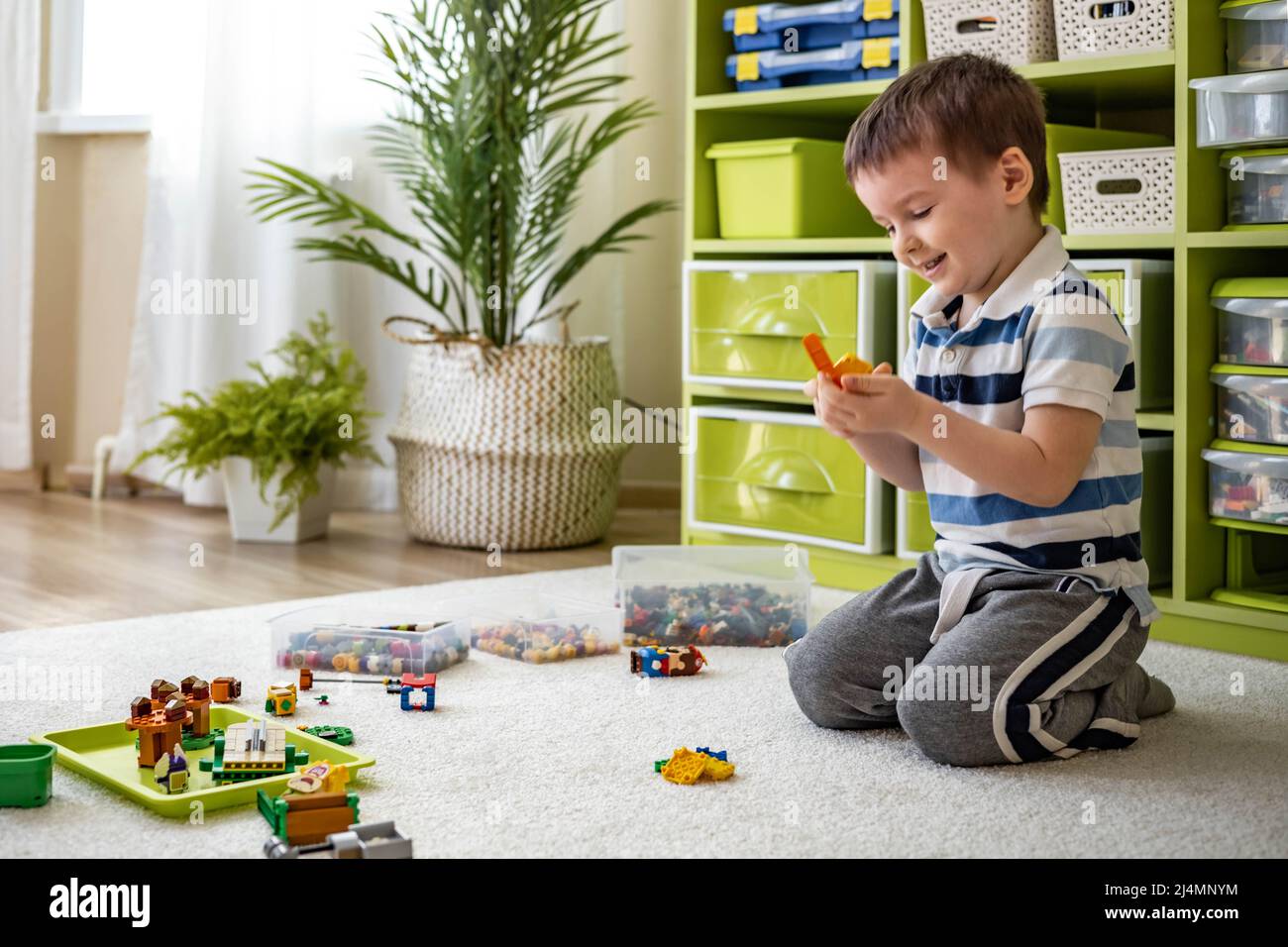 Khabarovsk, Russia, February 18, 2022. Boy constructs Lego at children's room toy storage system ...
