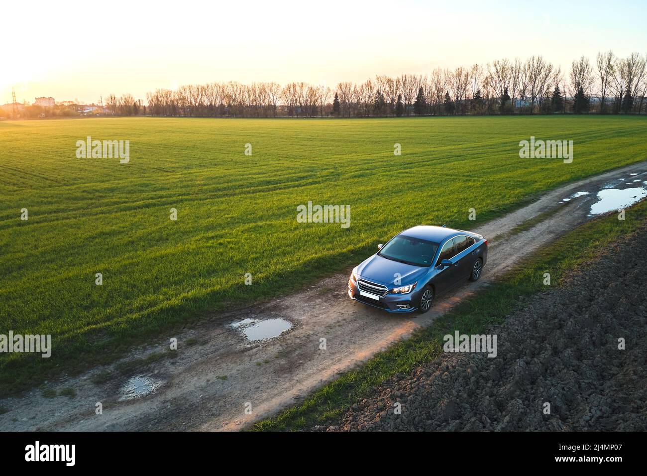 Aerial view of sedan car driving fast on dirt road at sunset. Traveling ...