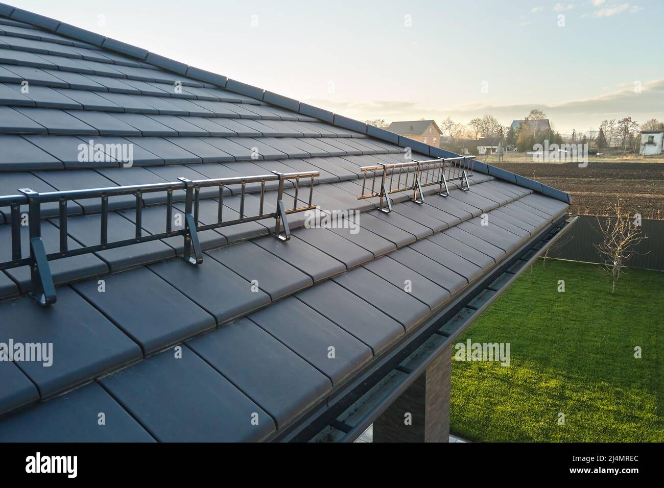 Closeup snow guard for safety in winter on house roof top covered with ...