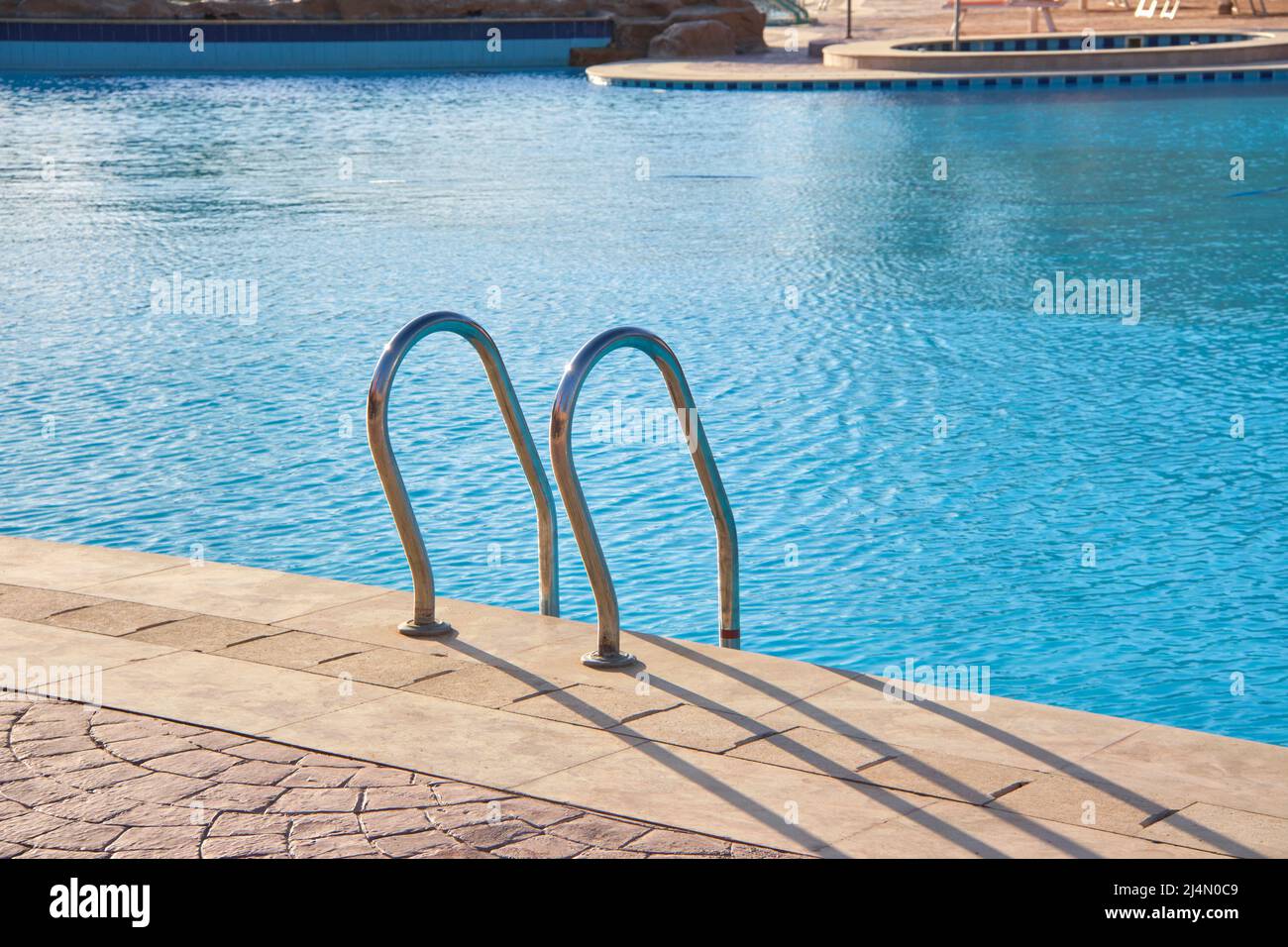 Close up of swimming pool stainless steel handrail descending into ...
