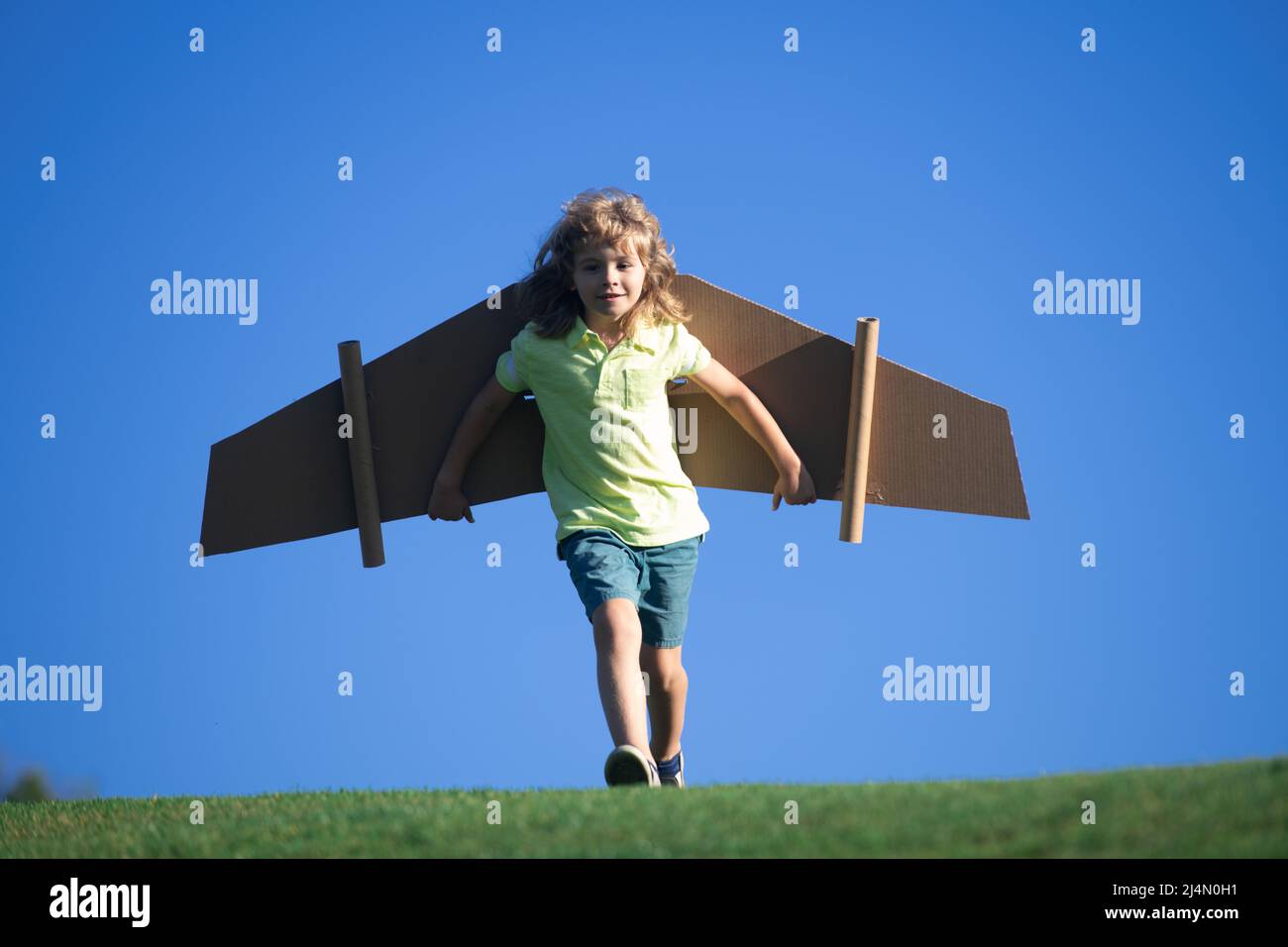 Child boy like a pilot with toy wings against blue sky. Kids freedom ...