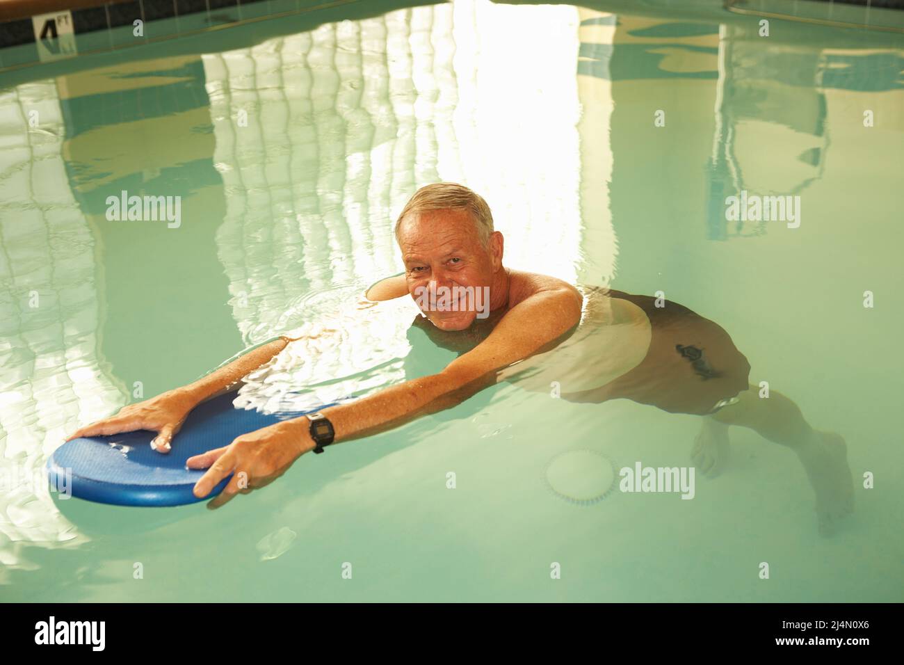 Mature male patient in hospital pool with flotation device during ...